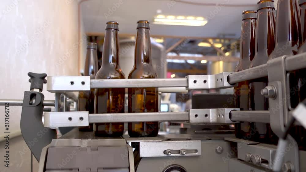 Automated beer bottling line. Beer bottles being loaded onto a conveyor ...