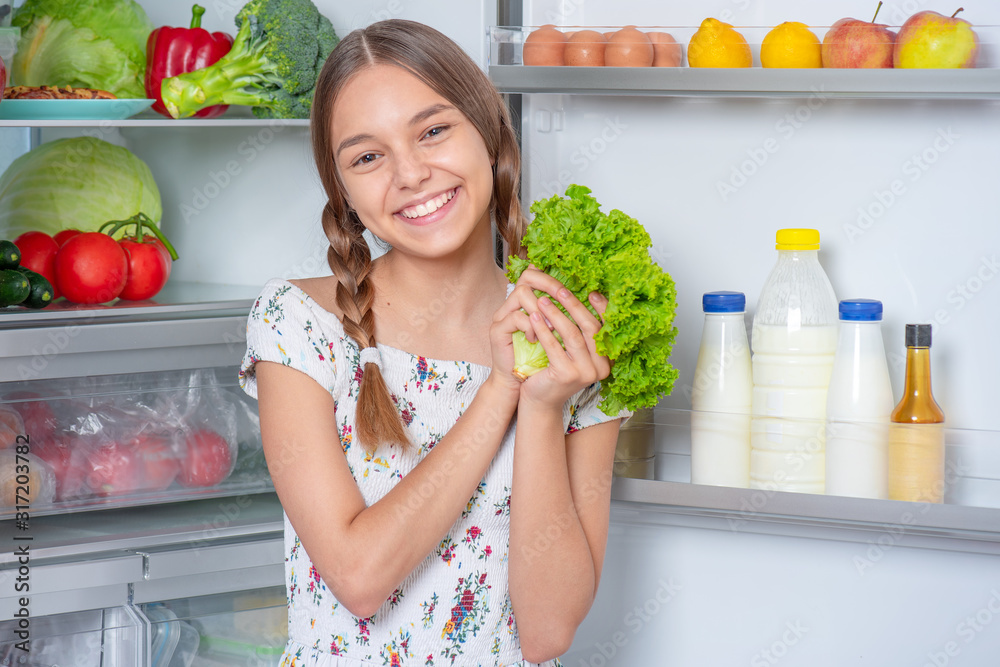 Smiling beautiful young teen girl holding fresh green salad while ...