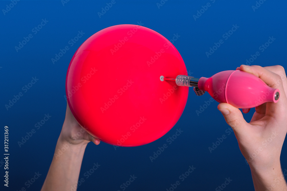 Hands inflating pink rythmic gymnastic ball ball with a hand pump ...