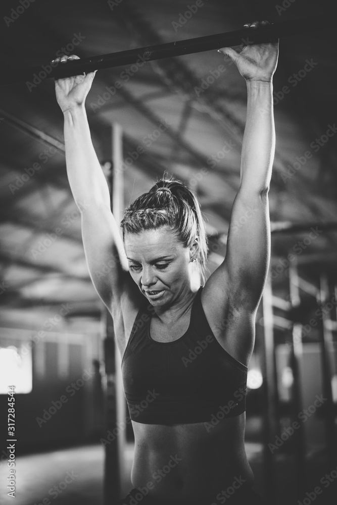 Female fitness model doing pull ups on a bar in a cross fit gym Stock ...