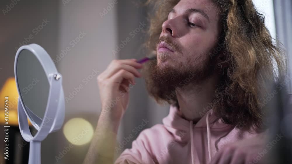 Shooting behind cosmetics, Caucasian male binary gender person applying ...