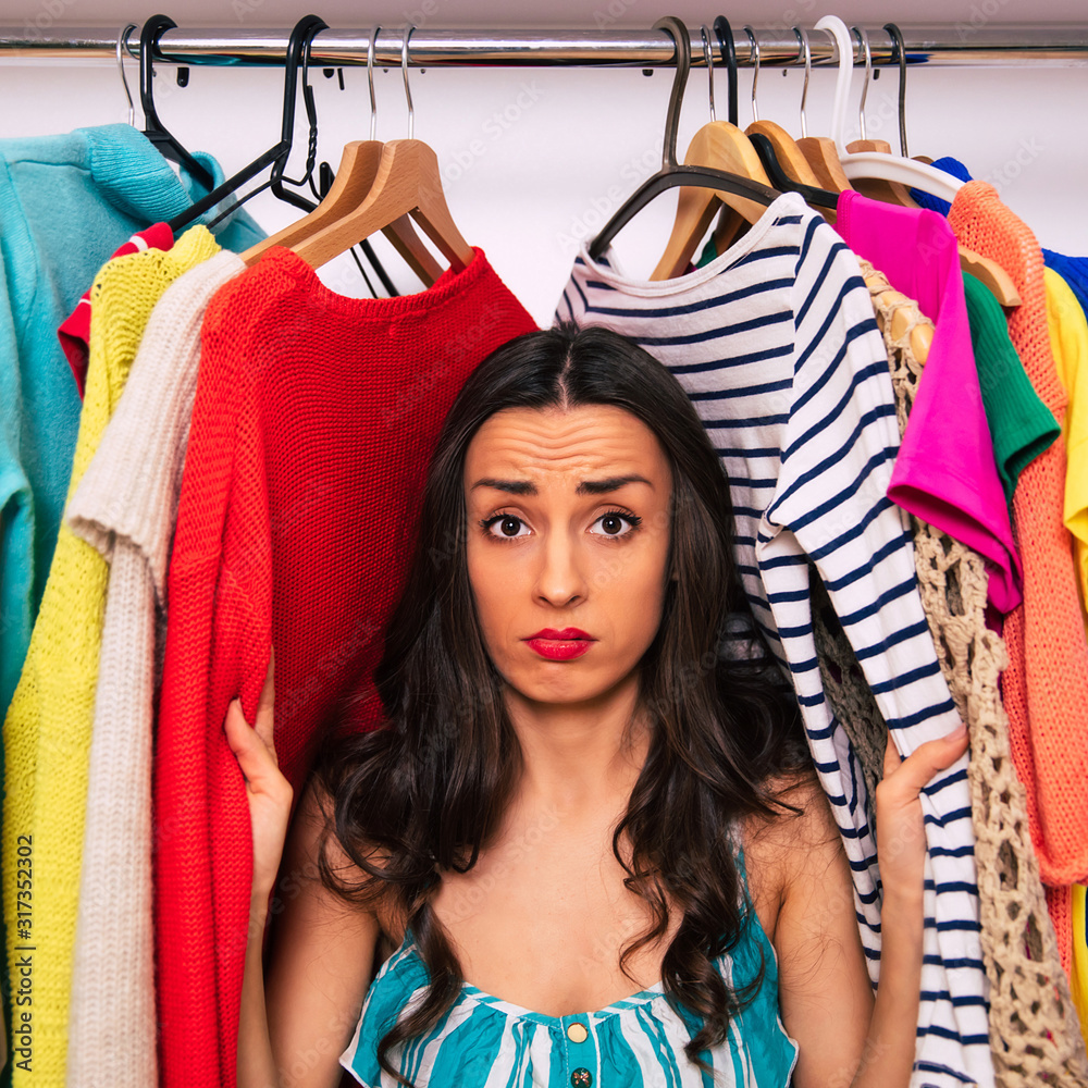Got lost in clothes. Close-up photo of a sad girl, who is looking in ...