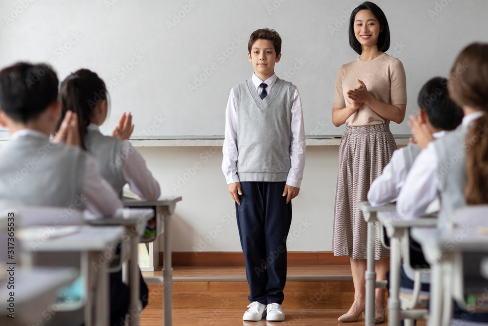 Young teacher introducing a new classmate in classroom Stock Photo ...