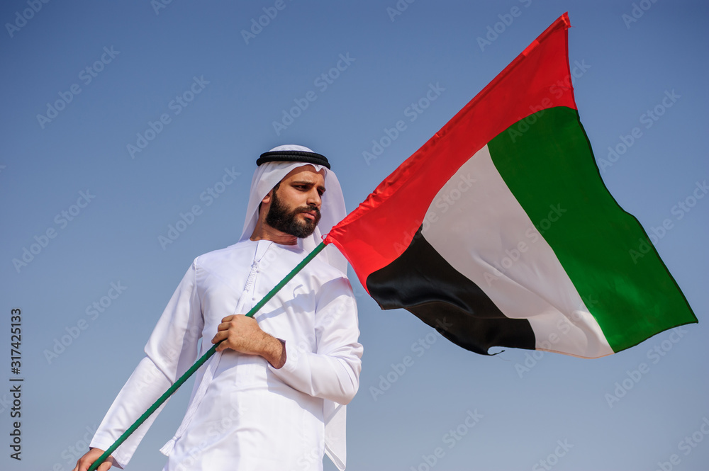 Proud arabian Emirati man holding a UAE flag in the desert. Stock Photo ...