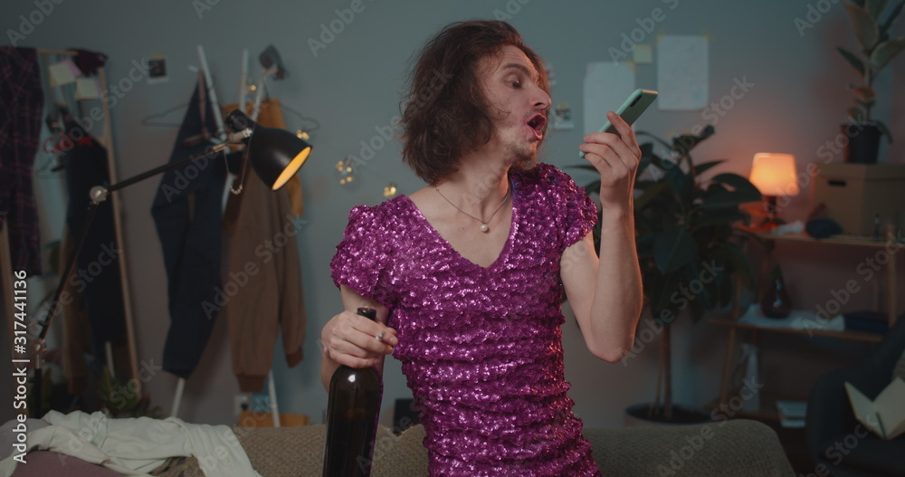 Front view of man transgender standing with wine bottle and yelling at ...