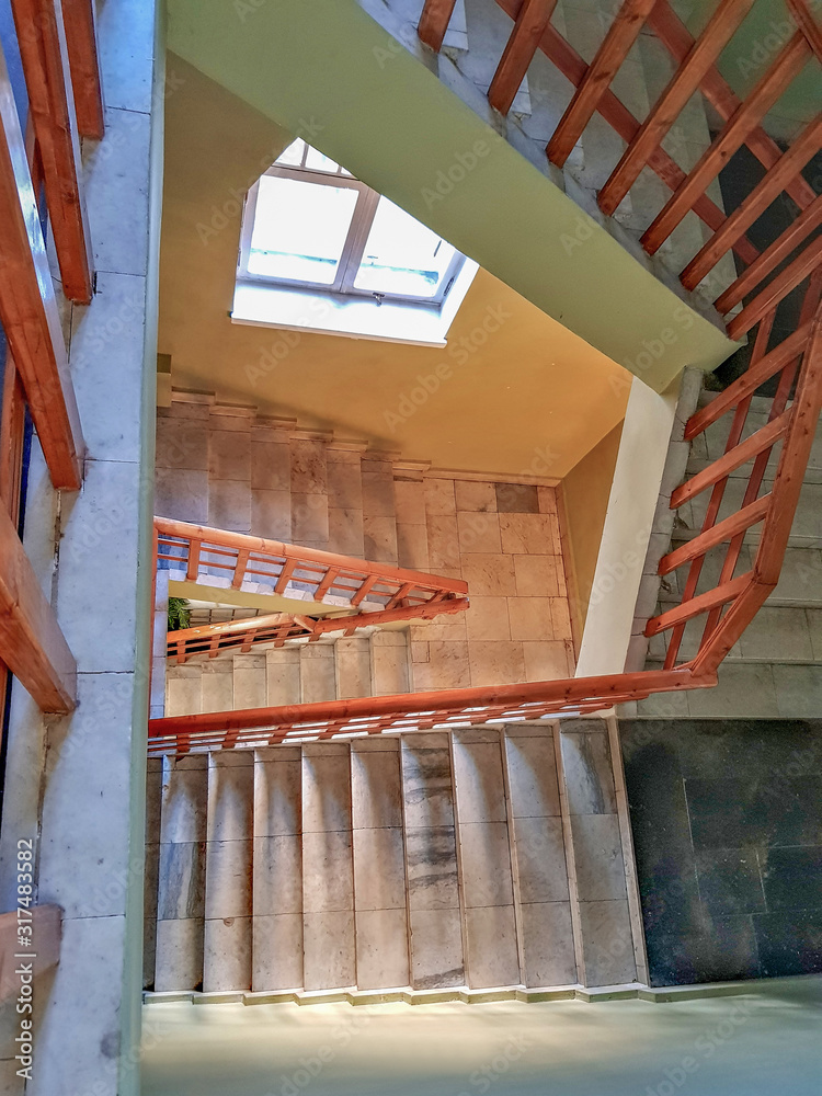 Old stone staircase with a handrail in a building without an elevator ...