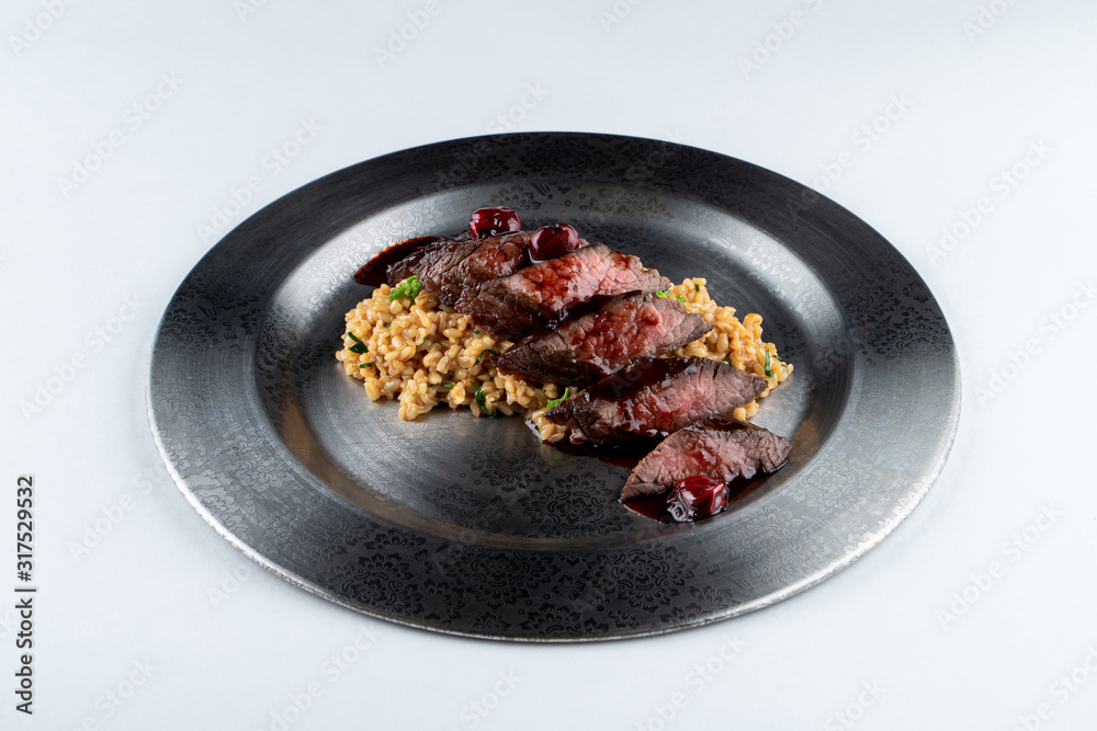 Medium rare pork steak with pearl barley and berry sauce isolated in ...