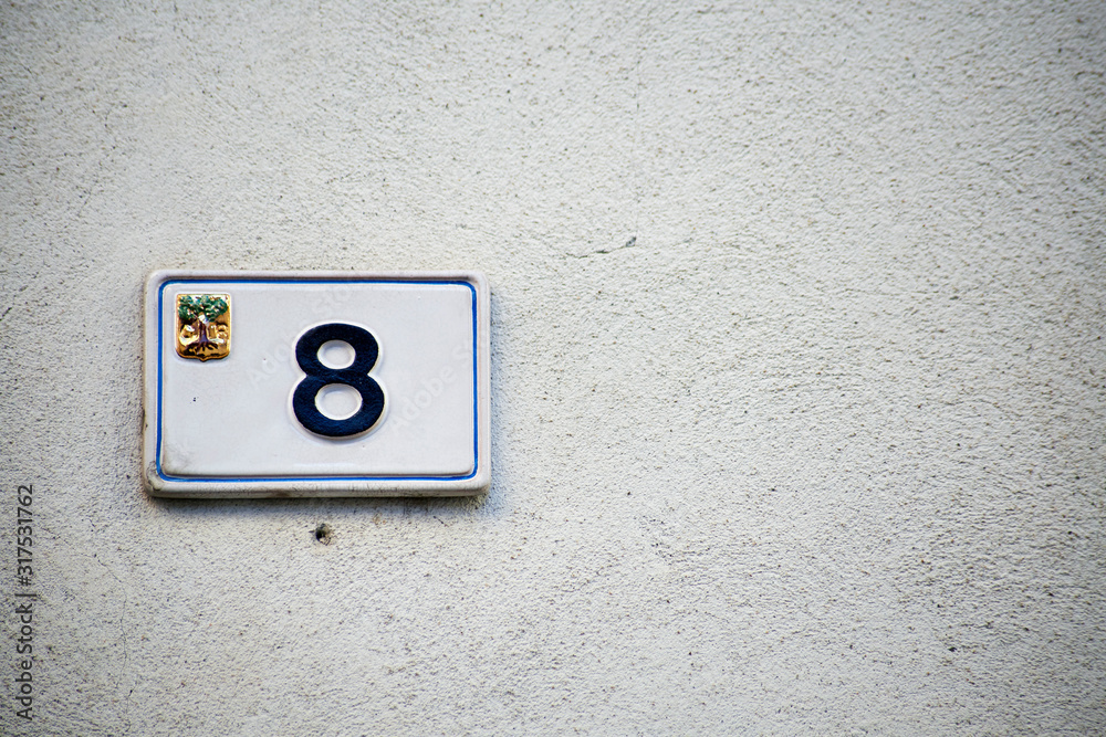 Italian house number ceramic plate sign mounted on the wall. With ...