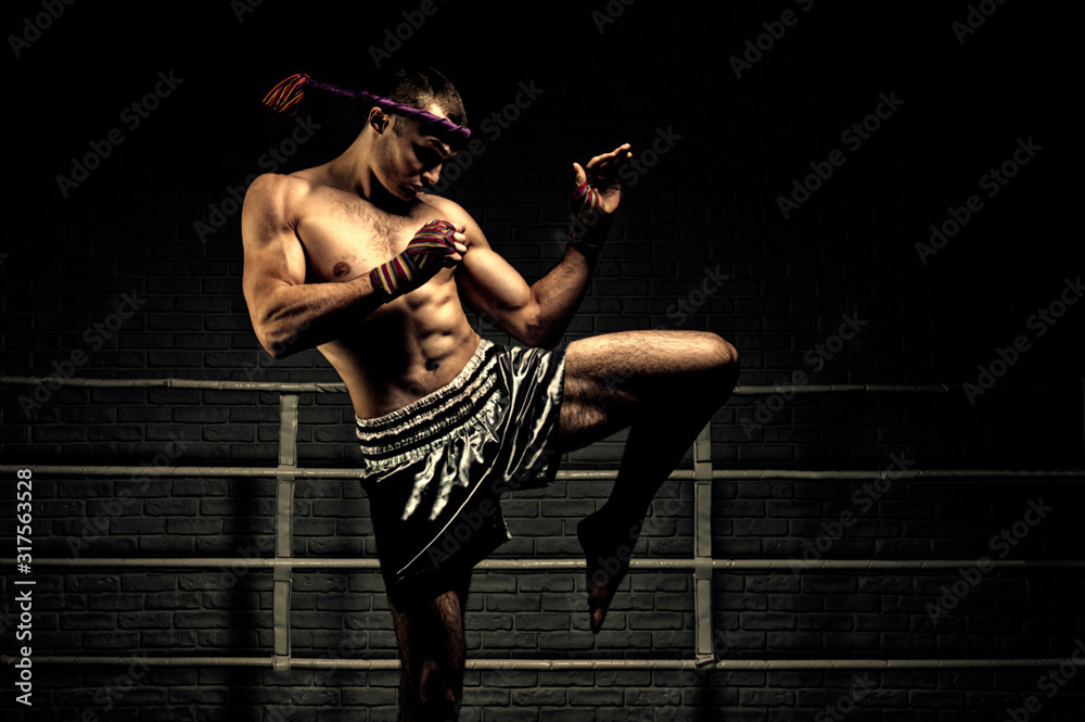 Kickboxer in the ring surrounded by searchlights stretches before the ...