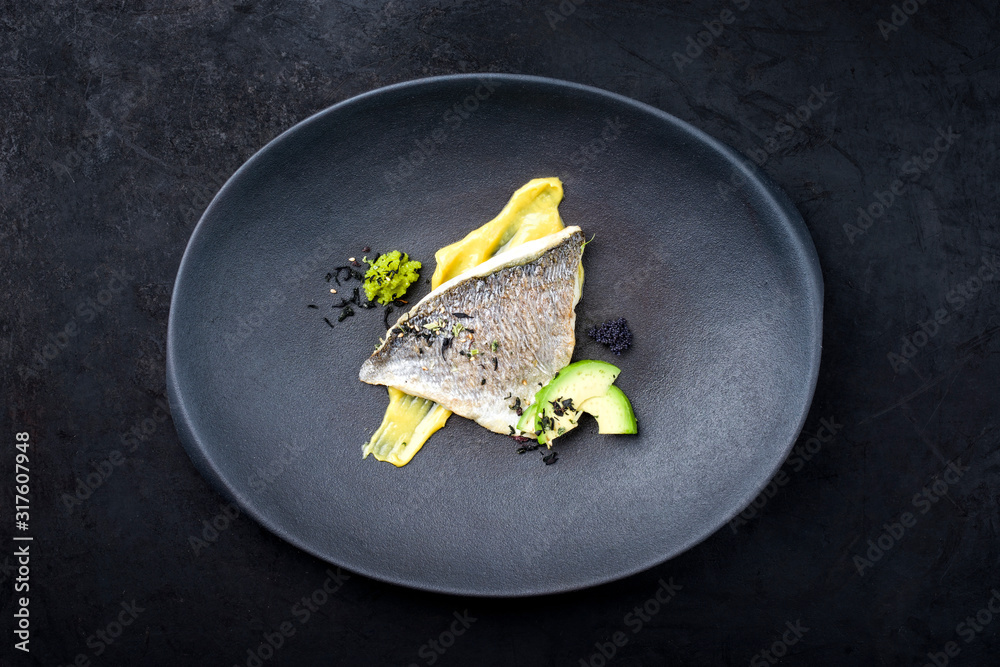 Gourmet fried gilthead fish filet with caviar, avocado slices and ...