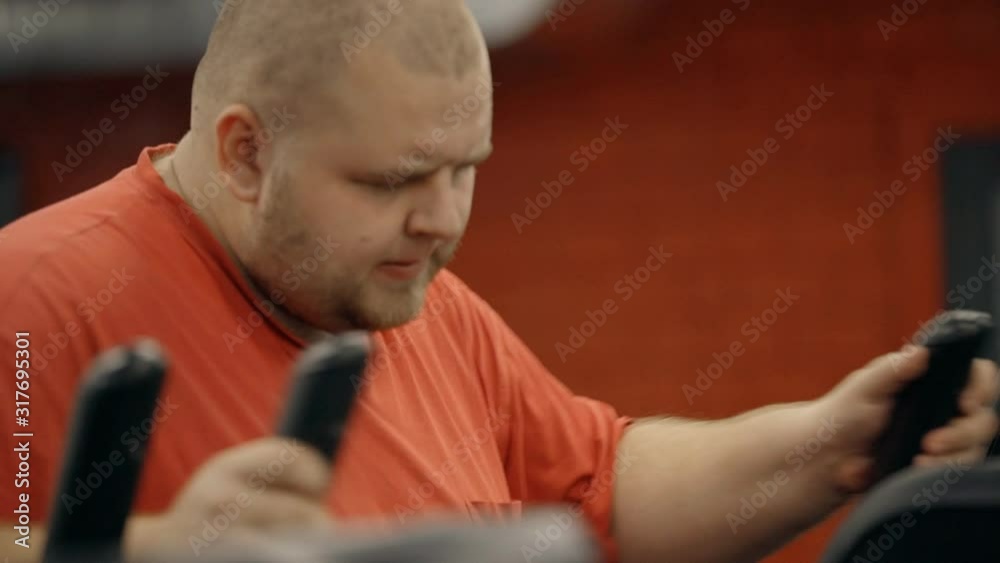 Tired overweight fat man standing inside modern and large sport gym. He ...