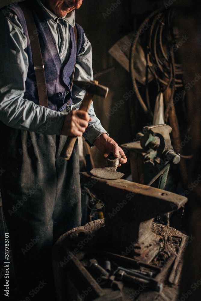 Old man working with hammer in the blacksmith. Stock Photo | Adobe Stock