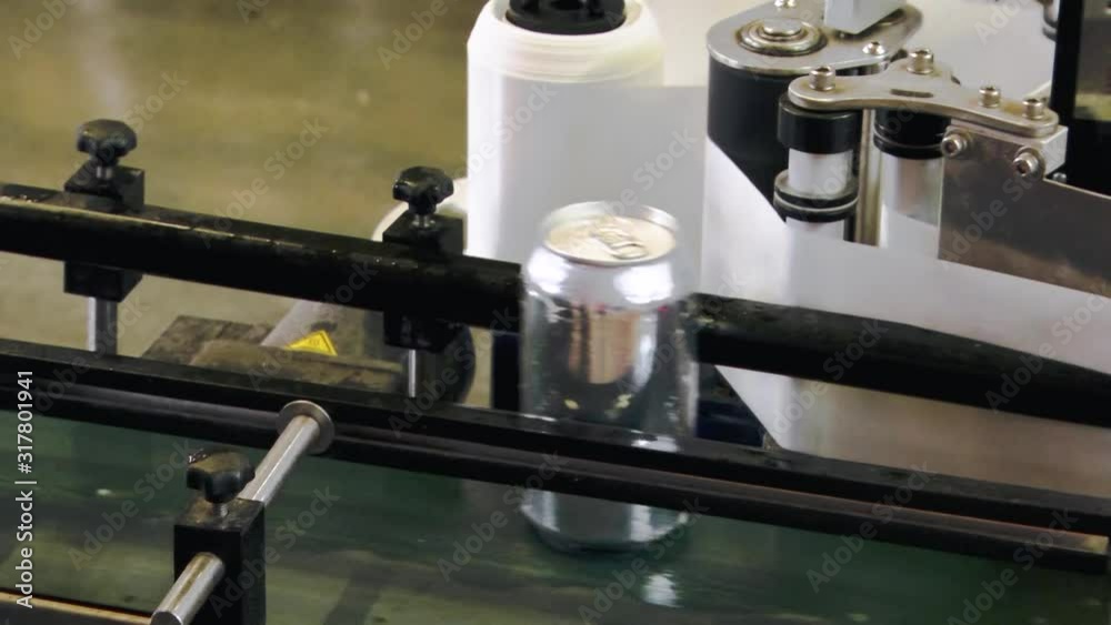 Production brewery worker's hand setting down full beer cans on a ...