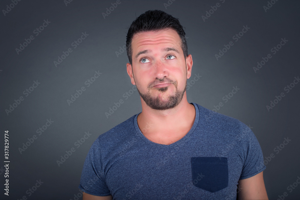 Gloomy, wondering young man face looking up lips together, being upset ...