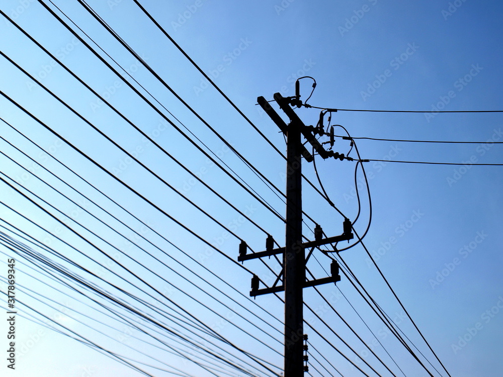 Silhouettes of high tension and low tension power lines on poles. On ...
