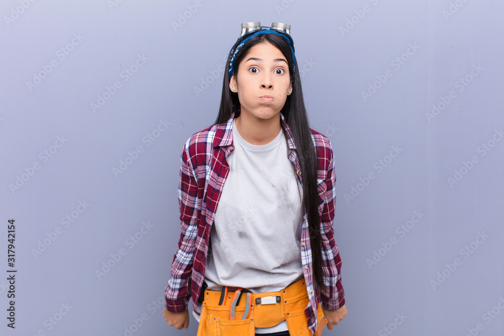 young latin woman with a goofy, crazy, surprised expression, puffing ...