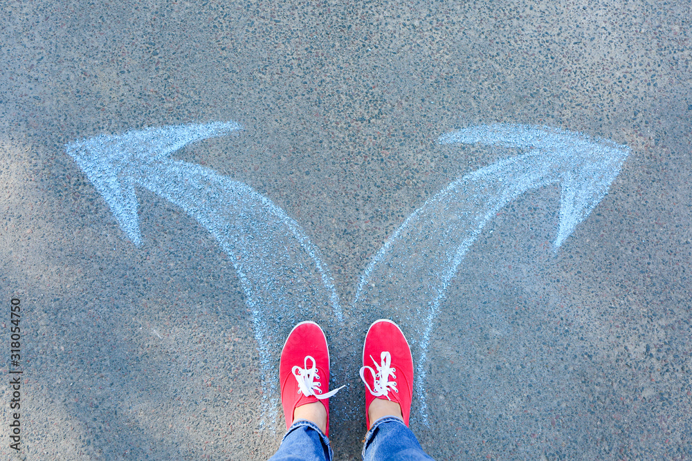 Person standing on road with arrows pointing in different directions ...