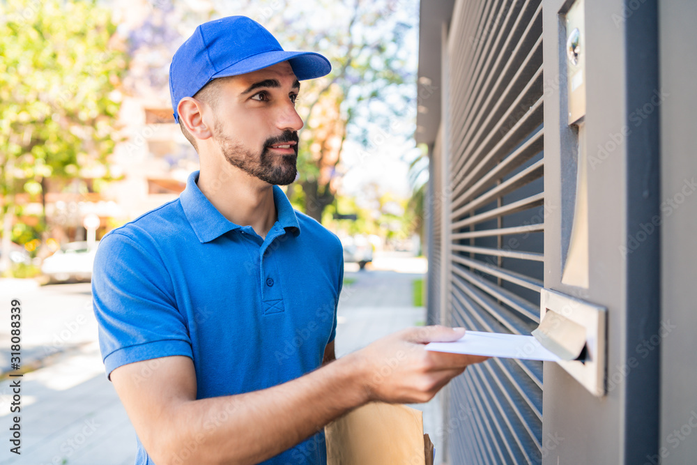 Postman putting letter in mailbox. Stock Photo | Adobe Stock