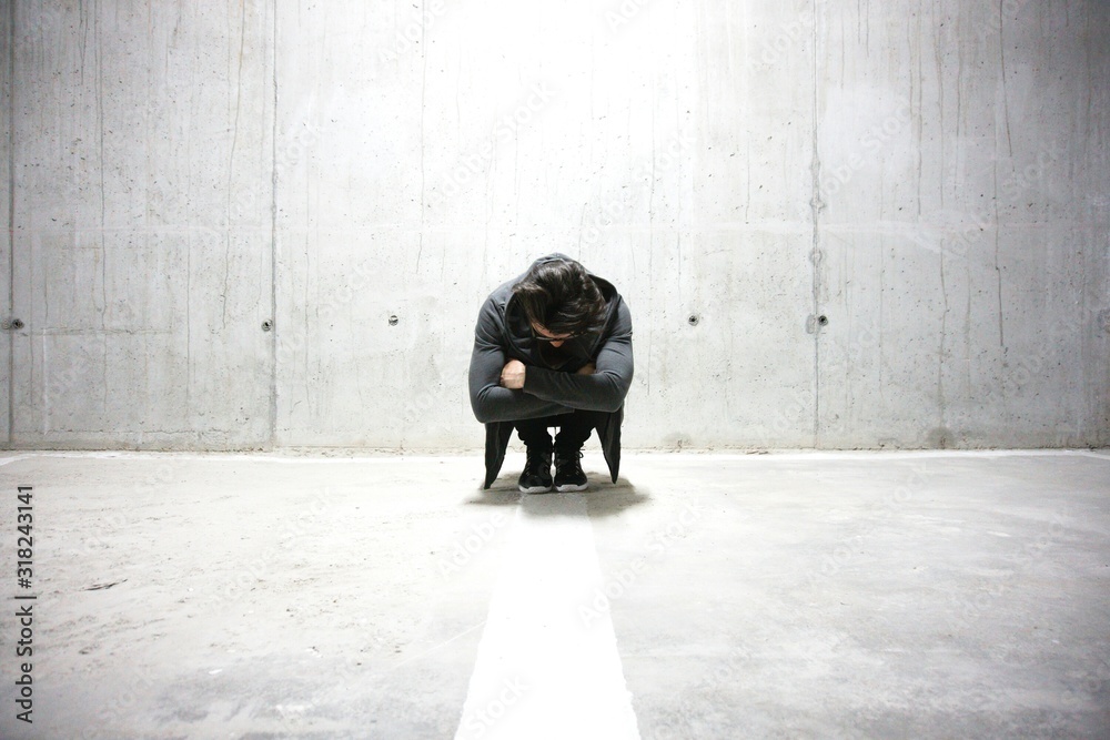 Full Length Of Sad Man Crouching In Illuminated Underground Parking Lot ...