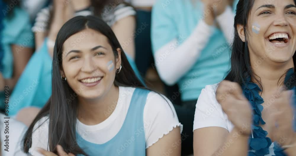Happy young sports fans at live game clapping and cheering for their ...