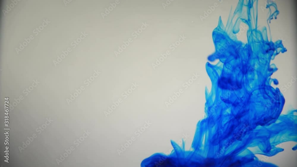 Blue color paint ink pouring over the glass with inky drops falling and ...