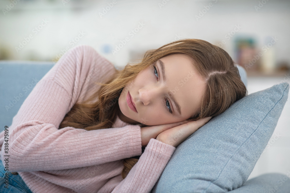 Sad girl lying on a sofa at home. Stock Photo | Adobe Stock