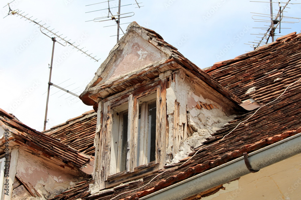 Destroyed old roof windows with cracked wooden frame on top of old ruins of abandoned suburban ...