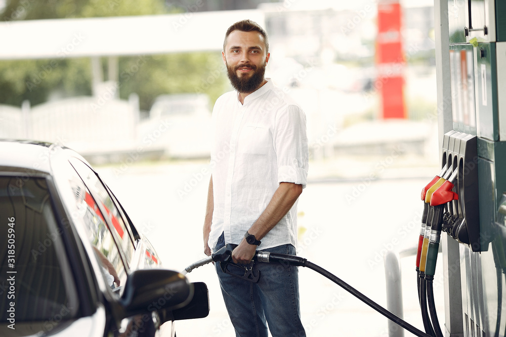 Man on a gas station. Guy refuelong a car. Male in a white shirt. Stock ...