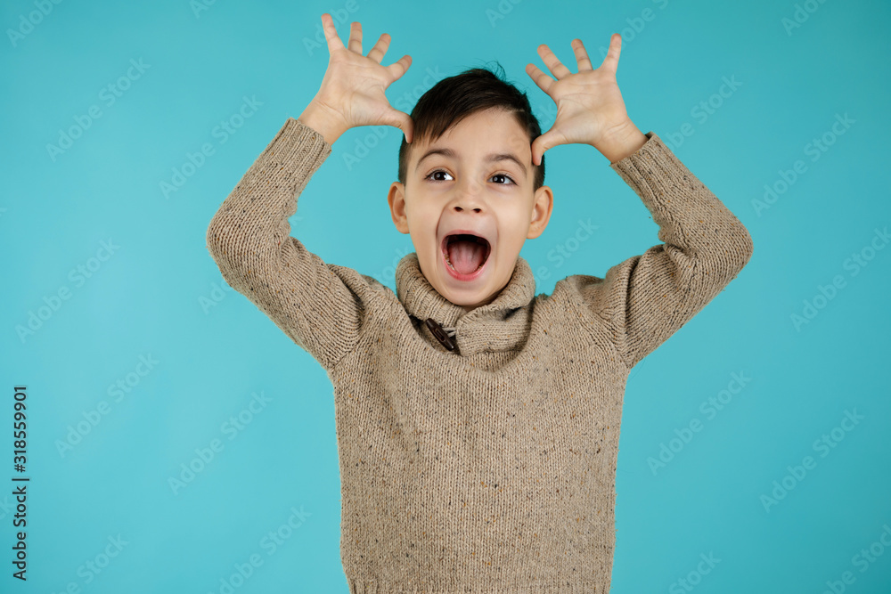 Cute scared little child boy looking at the camera on blue background ...