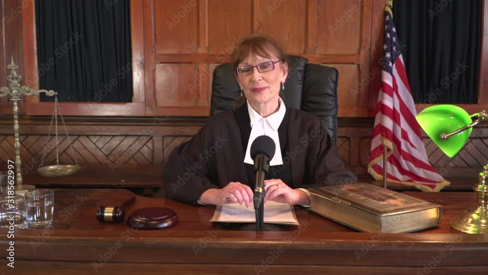 Female Judge sat at the bench in a Court. There is a USA flag behind ...