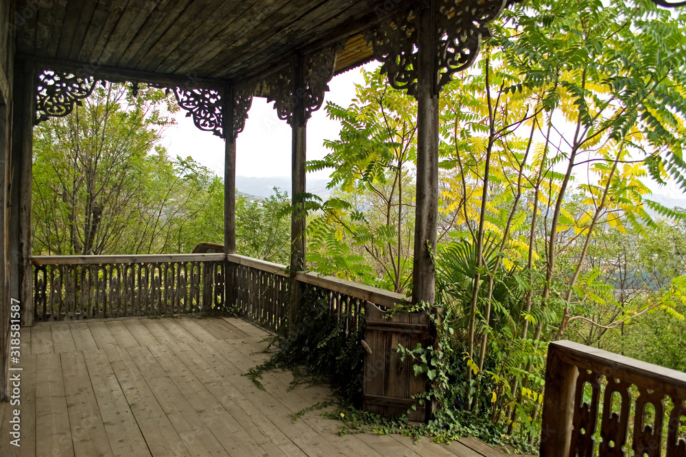 Empty abandoned wooden terrace of an old Georgian house. A wild forest ...