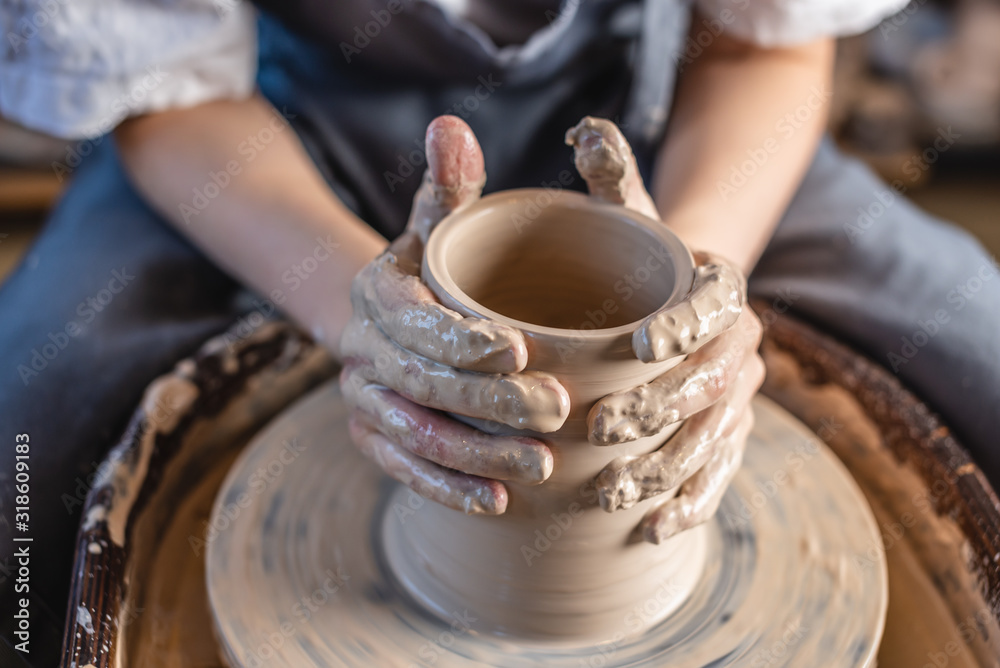 Potter working on a Potter's wheel making a vase. Woman forming the ...