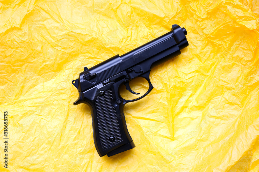 Gun lying on the yellow background. Legalising of weapon. Crime concept ...