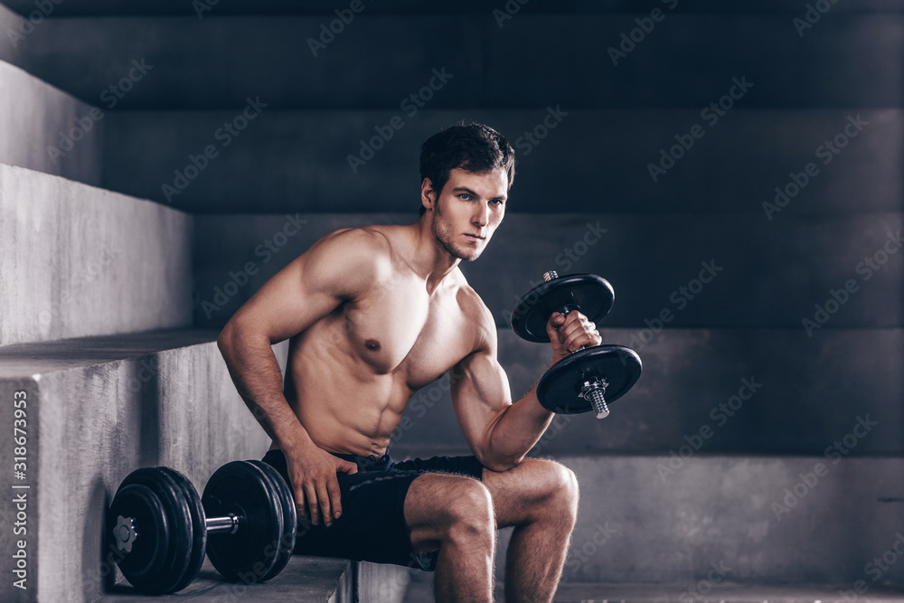 Strong muscle man sit and exercise biceps with heavy dumbbells. Stock ...