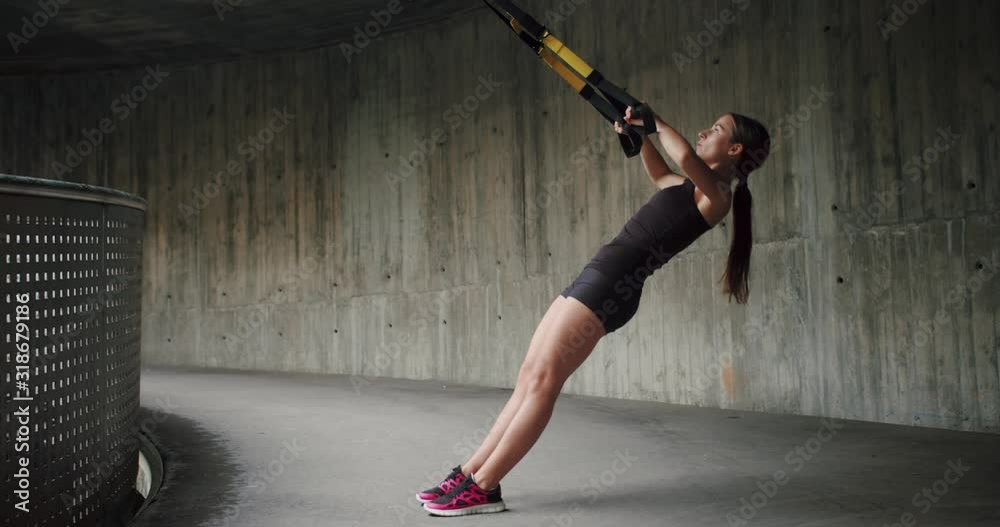 Concentrated strong young woman doing pull ups exercises alone using ...