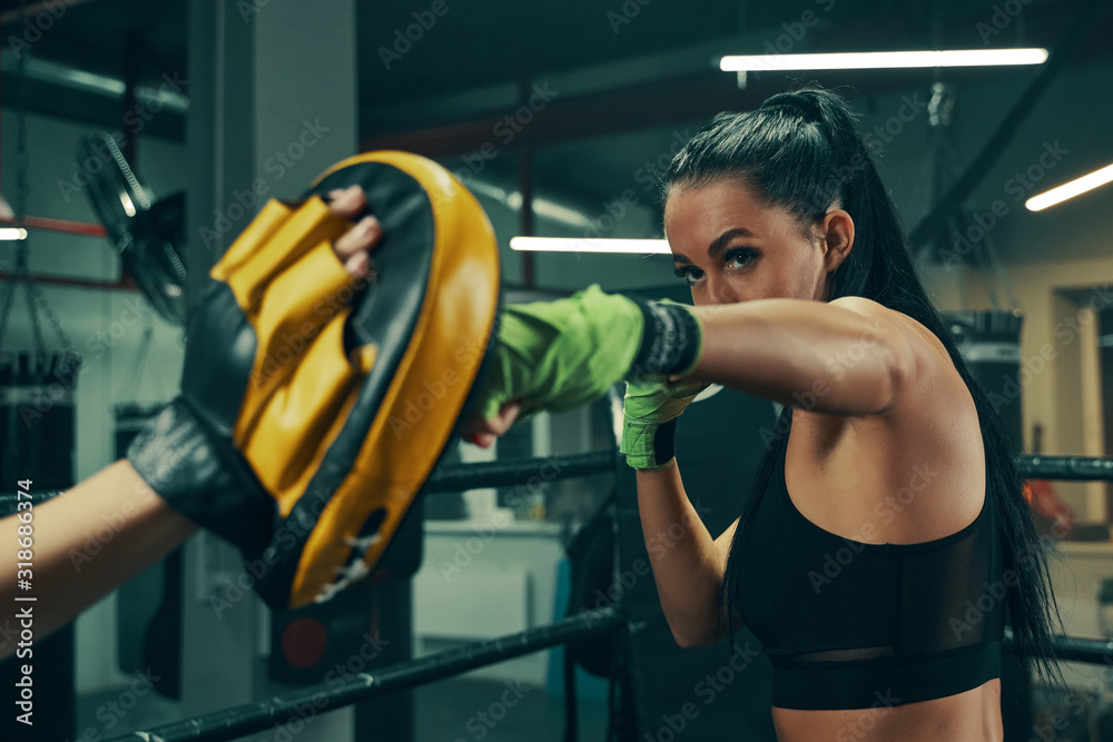 Athletic woman during fight training on boxing ring wearing green ...