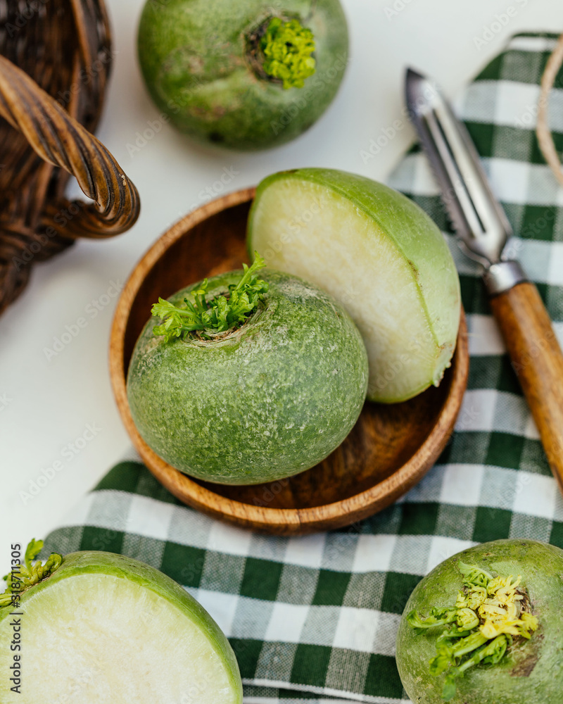 Green round radish whole and cut on a wooden plate. Menu for ...