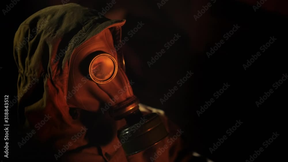 Side view of A person in a gas mask lights a fire of a fire vídeo de ...