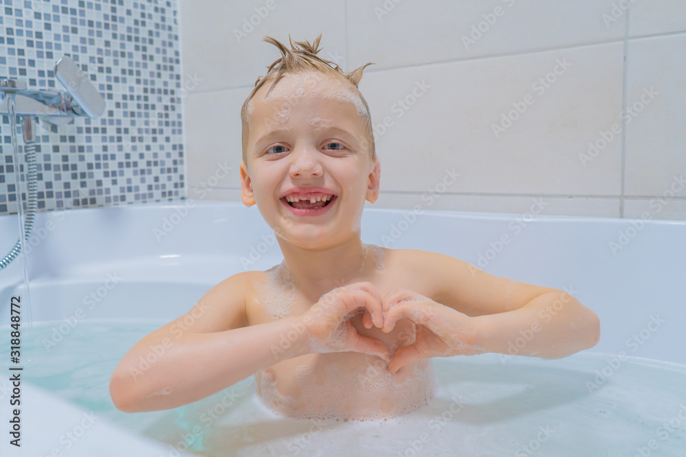 6-7 years old boy taking a bath, looking at the camera and hands depict ...