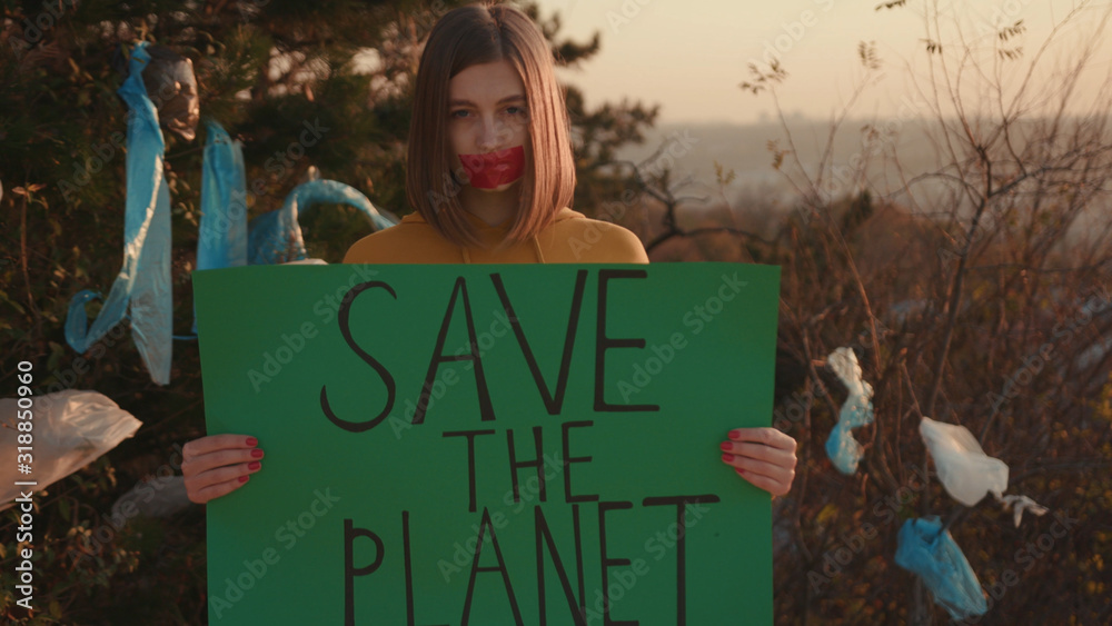 Sad young woman activist mouth glued holding encouraging green poster ...
