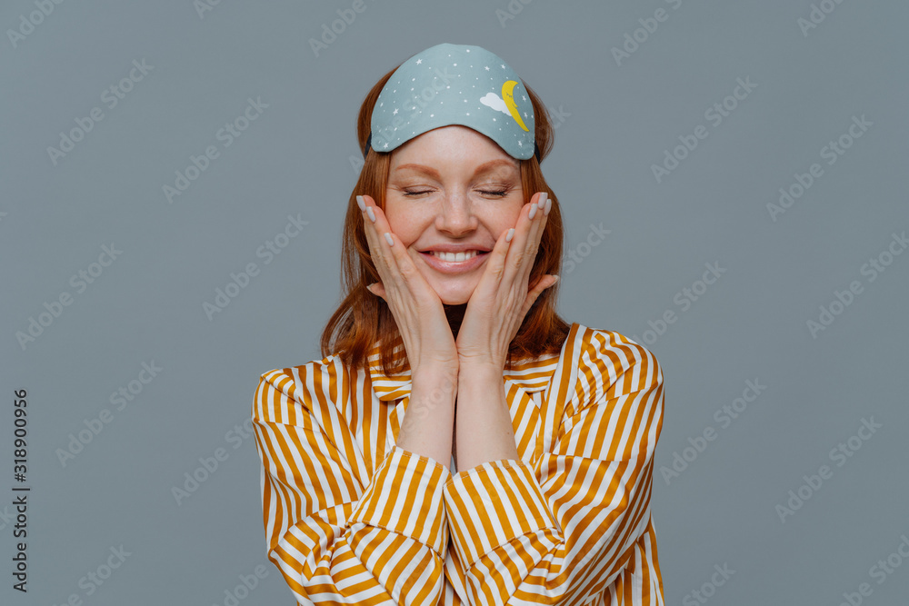 Pleased woman touches cheeks, has healthy freckled skin, smiles broadly ...