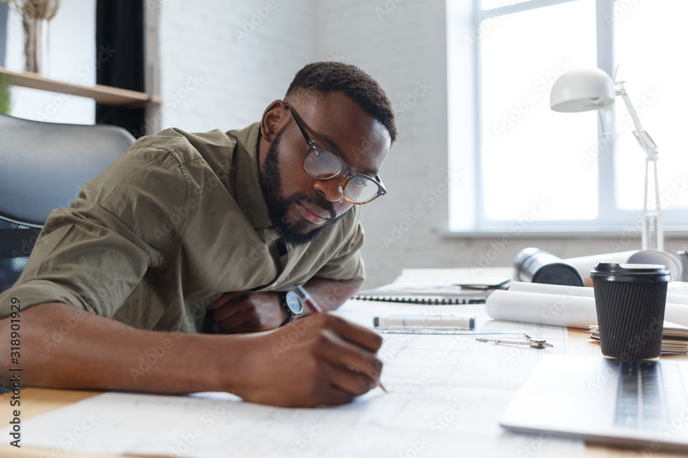 Afro-American architect working in office with blueprints.Engineer ...
