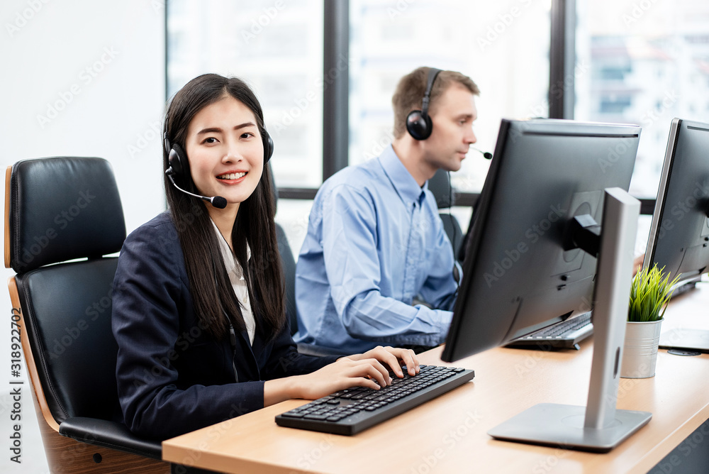 Beautiful Asian female call center employees are working. She turned to ...