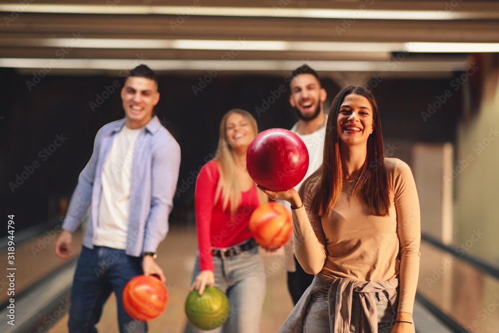 Beautiful group of young people posing in a bowling alley with a ball ...