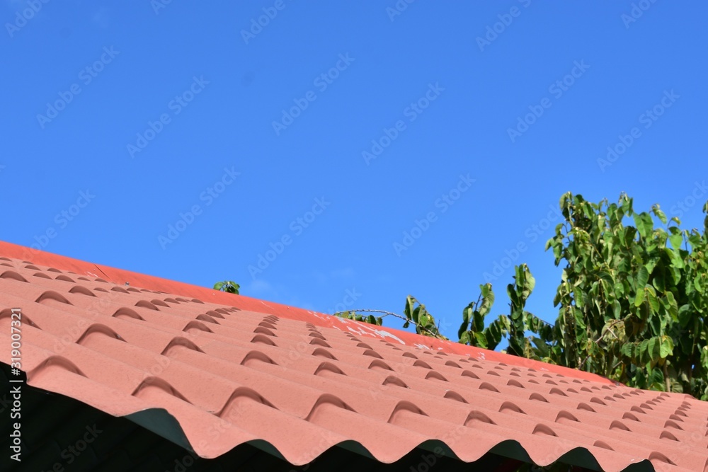 techo de teja roja con fondo de cielo azul y arbol de hojas verdes ...