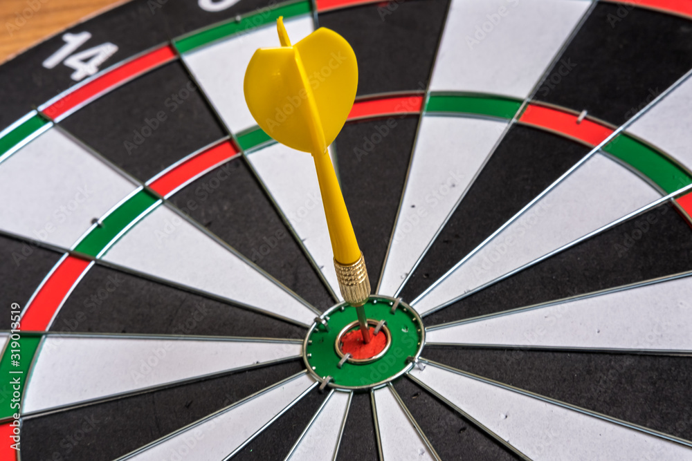 Red and yellow dart arrows hitting in the target center of dartboard ...