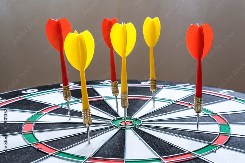 Red and yellow dart arrows hitting in the target center of dartboard ...