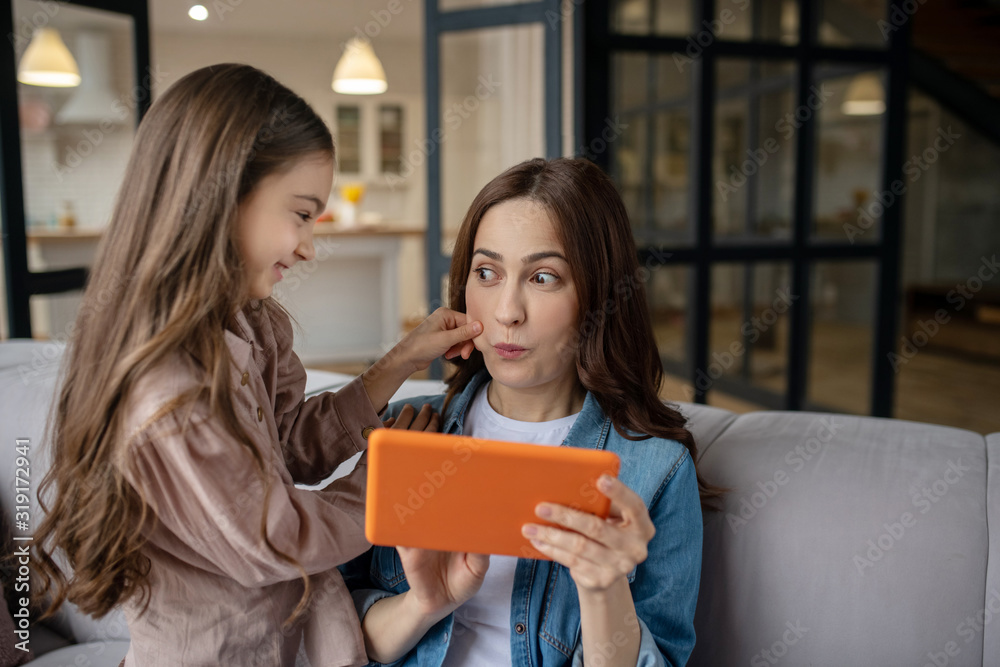 Mom making facial expressions to make her daughter laugh. Stock Photo ...