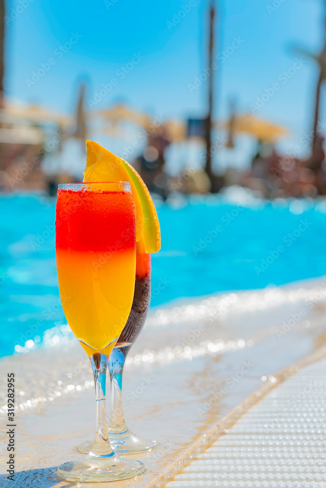 Two cocktails with natural juice and ice at the edge of the swimming ...