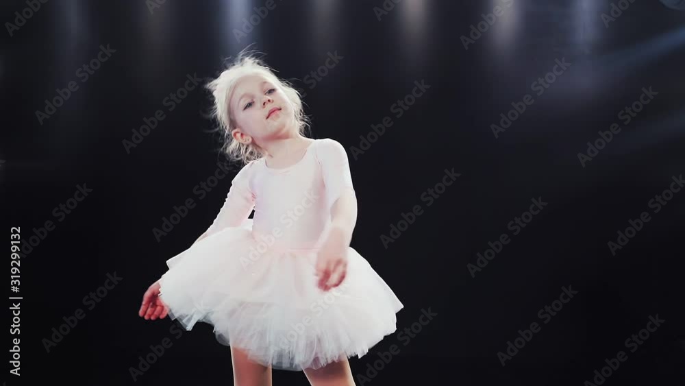 Little girl ballerina Caucasian appearance in a white tutu dances on ...